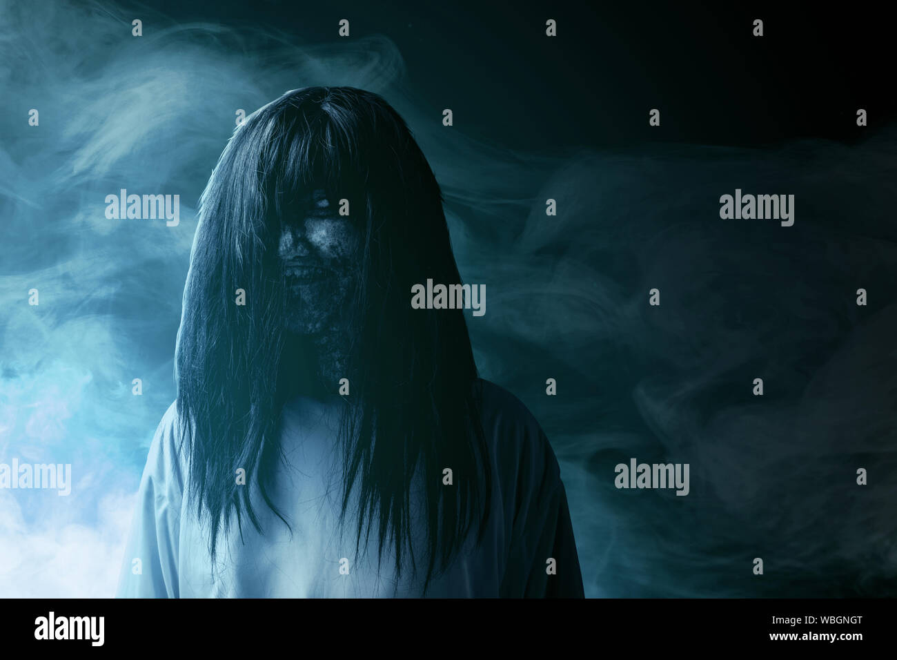 Scary ghost woman with blood and dirty face standing amid the dark fog ...
