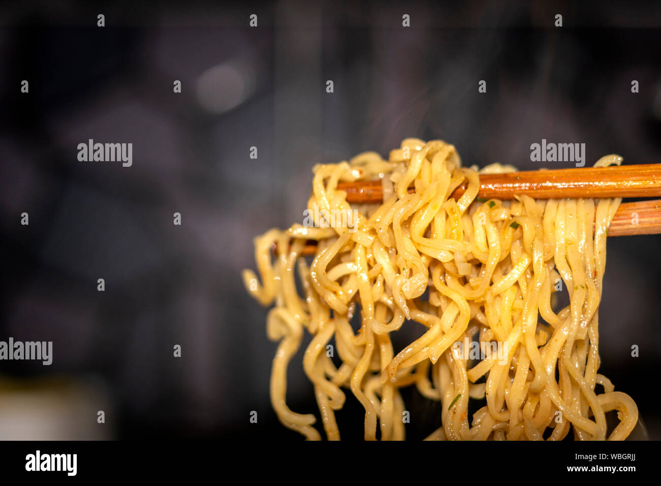 Close up instant noodles in a bowl. Hand holding bamboo chopsticks ...