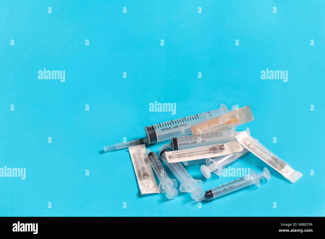 Vials with medication and injection needle on blue background. Multiple ...