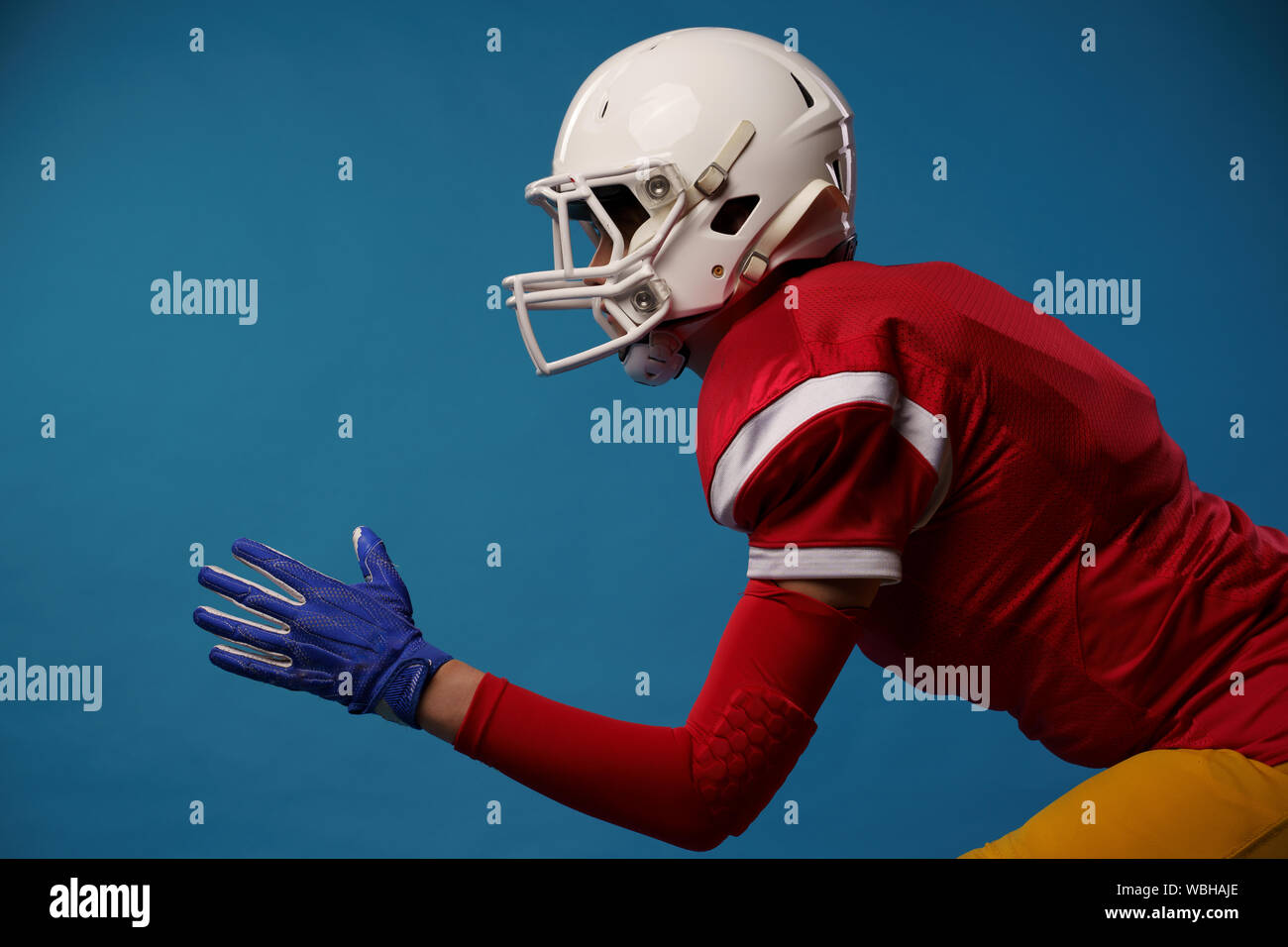 Side view of running woman of american football player on blue ...