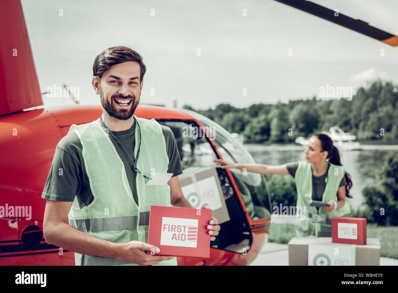 Volunteer feeling cheerful sending first aid boxes with colleague Stock ...