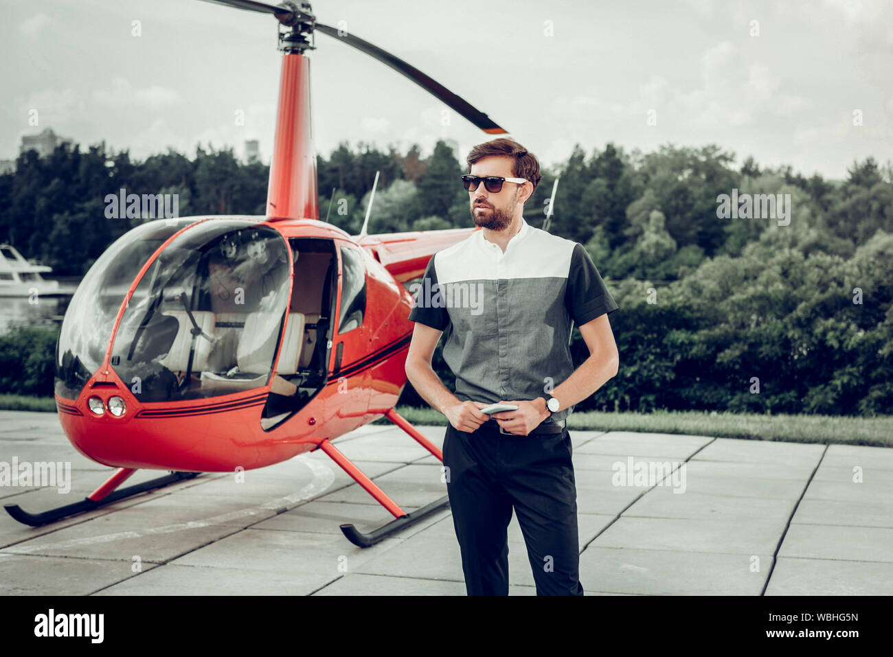 Stylish rich businessman standing near his little private helicopter ...