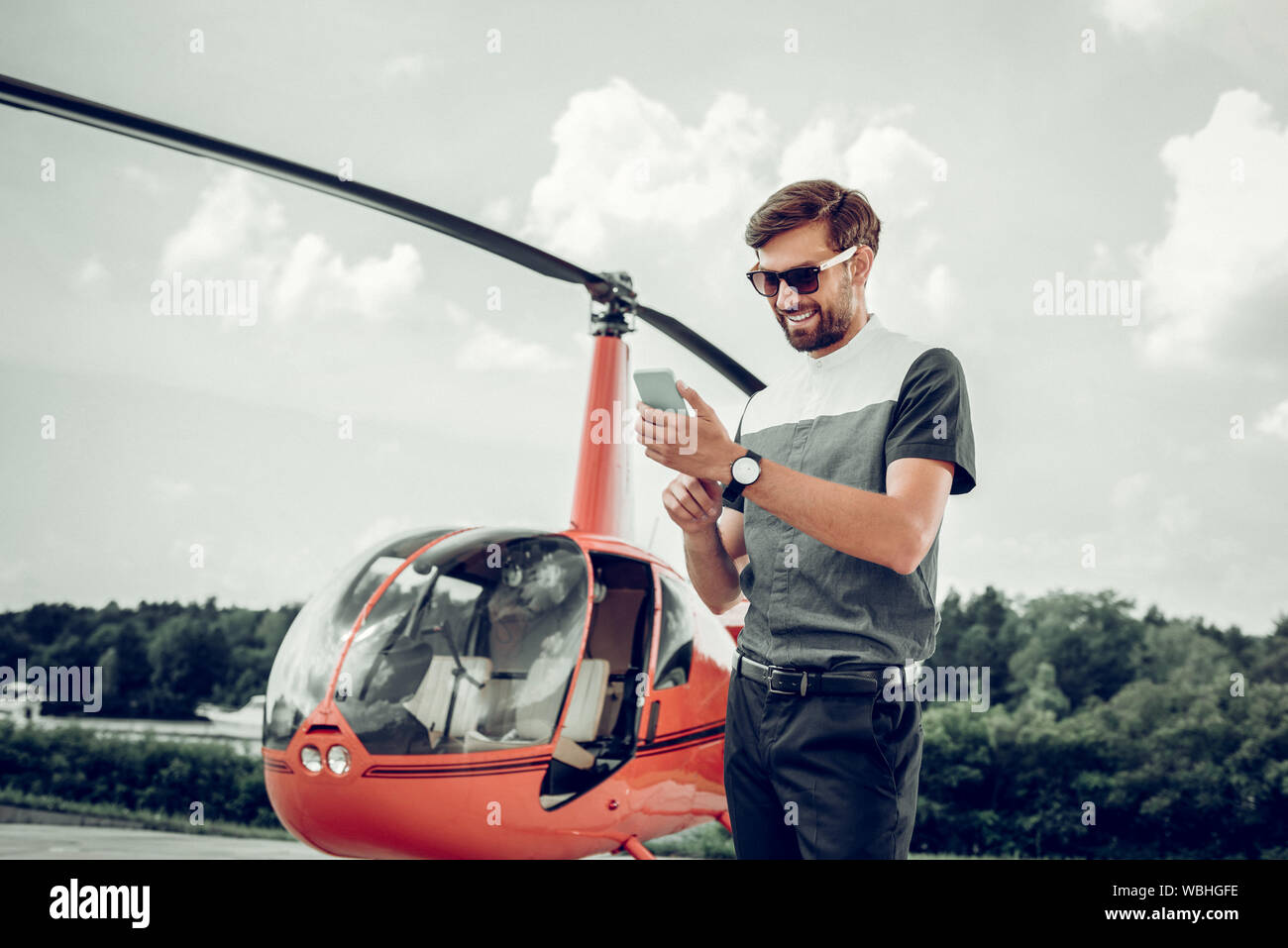 Prosperous successful man texting his wife after flight in helicopter ...