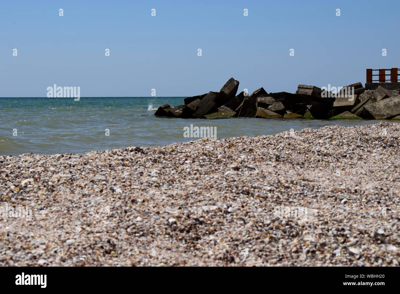 Pier and rocks. Sea piercing with a pier equipped with wooden railings ...