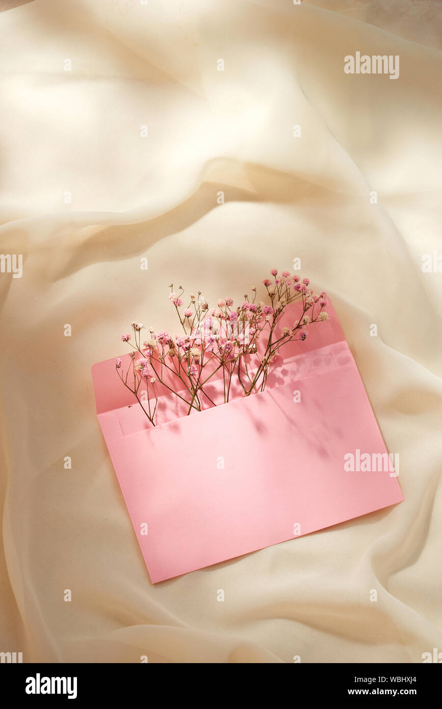 Pink envelope with a spring flower arrangement. Flat lay, top view ...