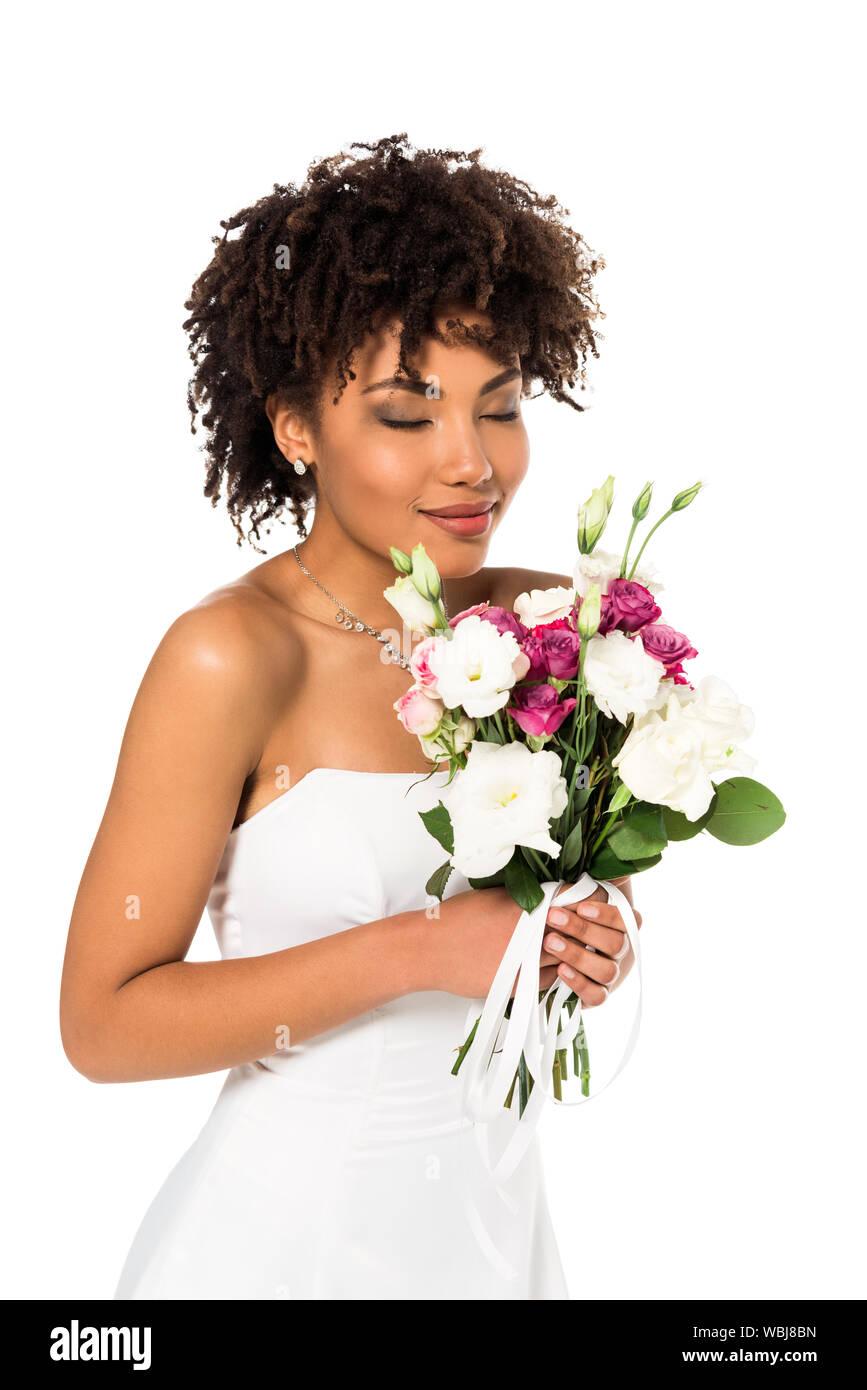 happy african american bride holding bouquet while smelling flowers ...