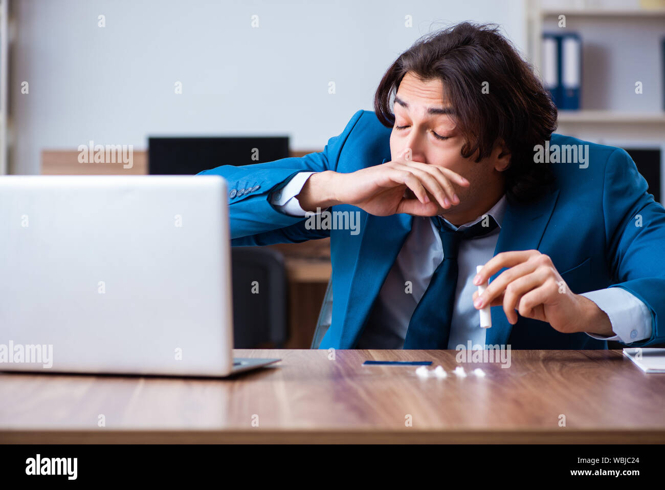 The young man having problems with narcotics at workplace Stock Photo ...