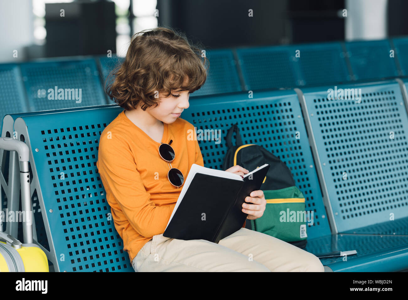 preteen kid sitting in waiting hall and writing in notebook Stock Photo ...