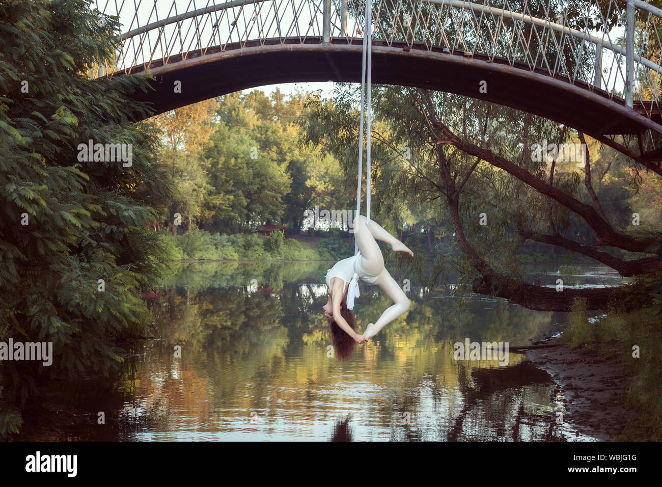 Young acrobat does tricks on white canvases over the river Stock Photo ...