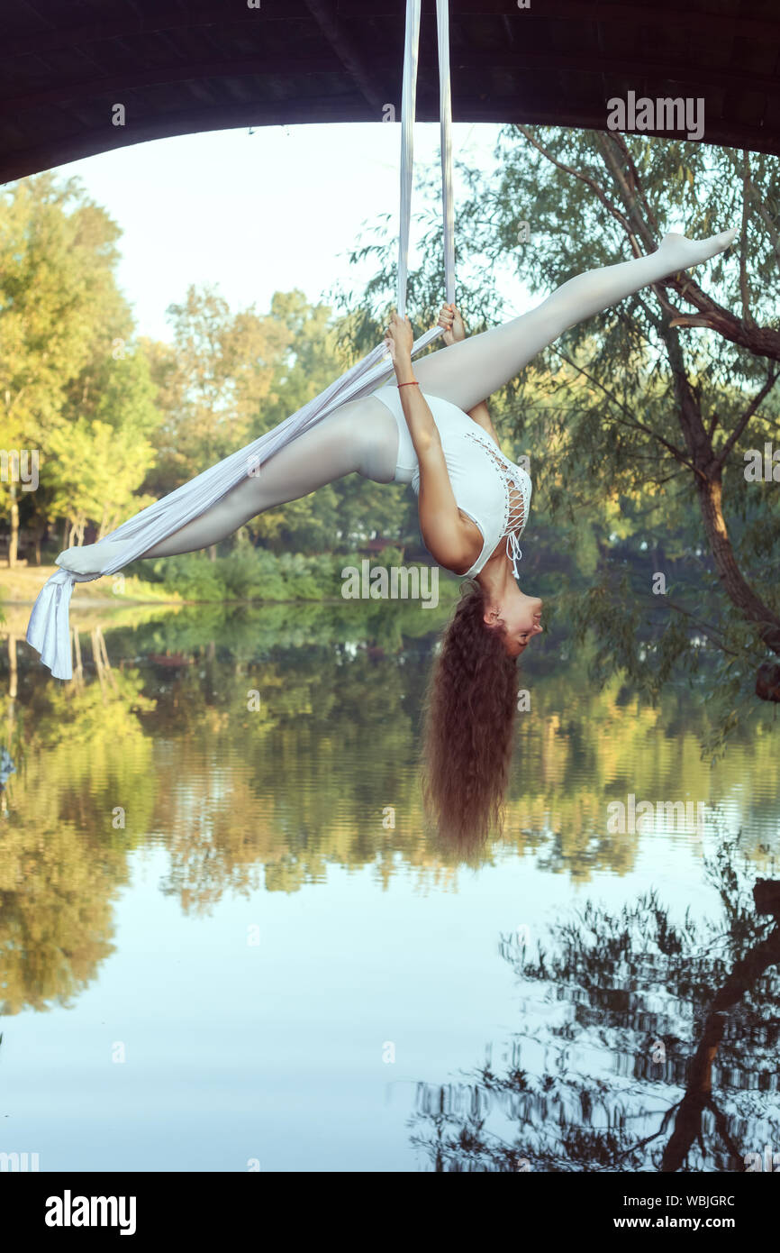 Portrait of a beautiful acrobat on canvases over the river. She does ...
