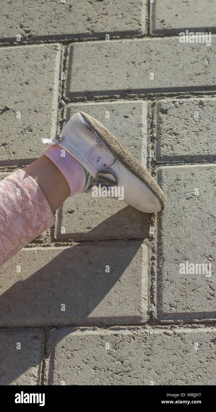 The tiny foot of a child in a small white leather shoe isolated on a ...