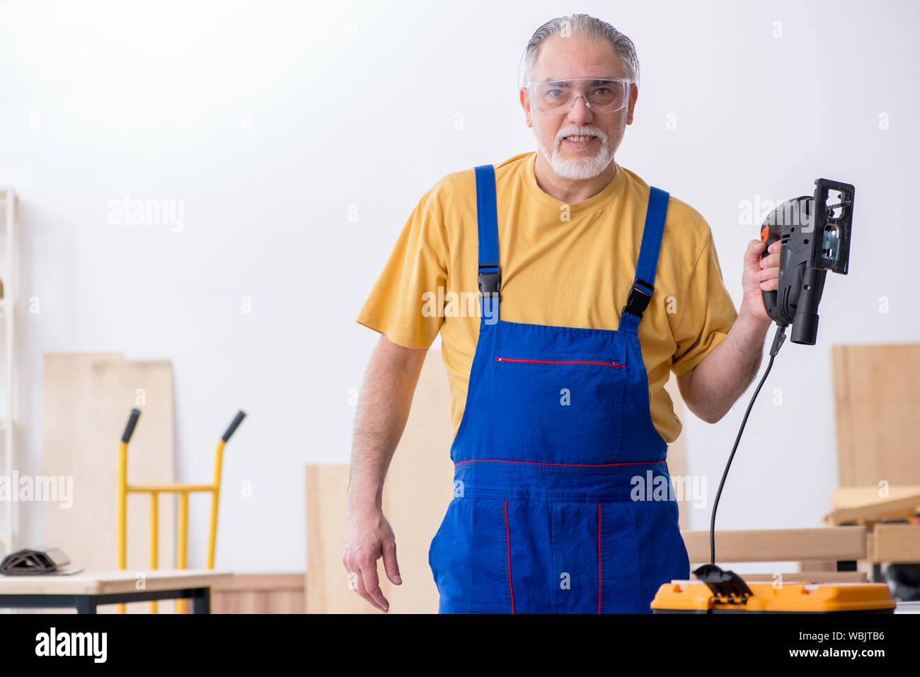 The old male carpenter working in workshop Stock Photo - Alamy