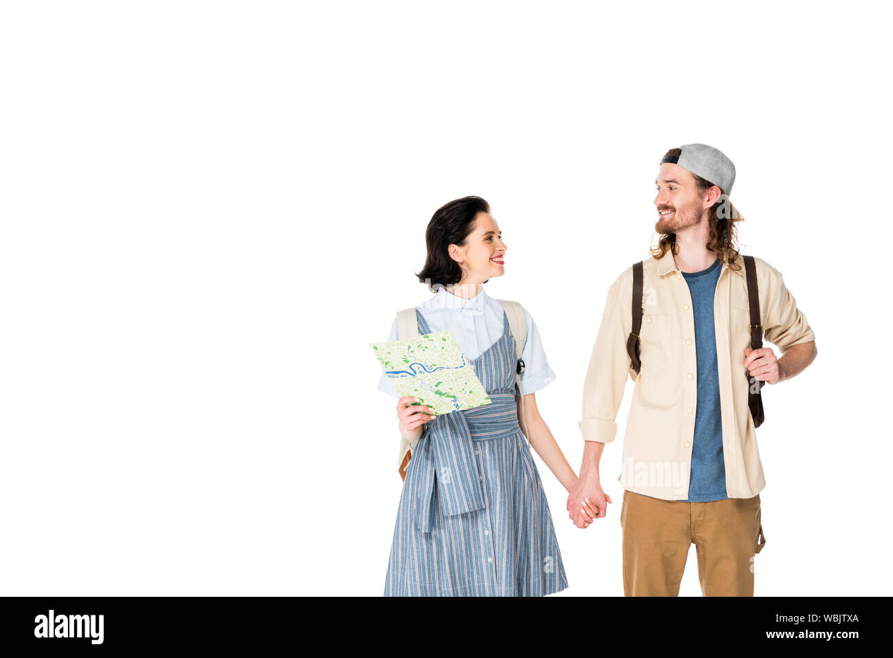 front view of girl holding map and young man holding hands and smiling ...