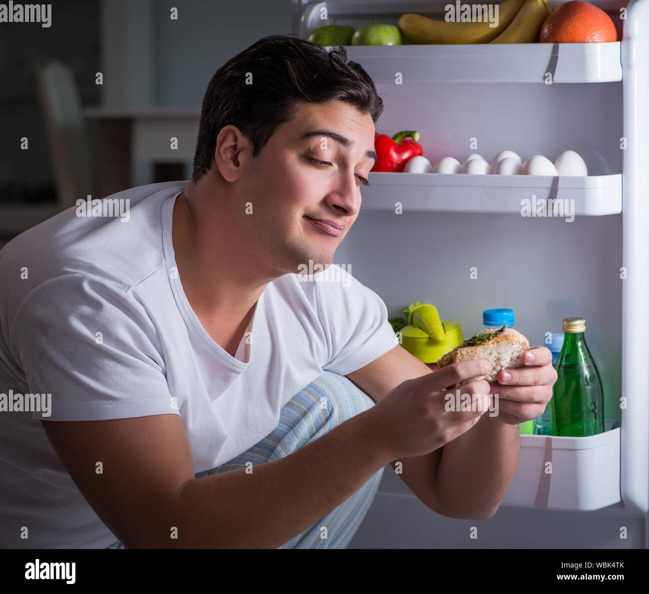 The man at the fridge eating at night Stock Photo - Alamy