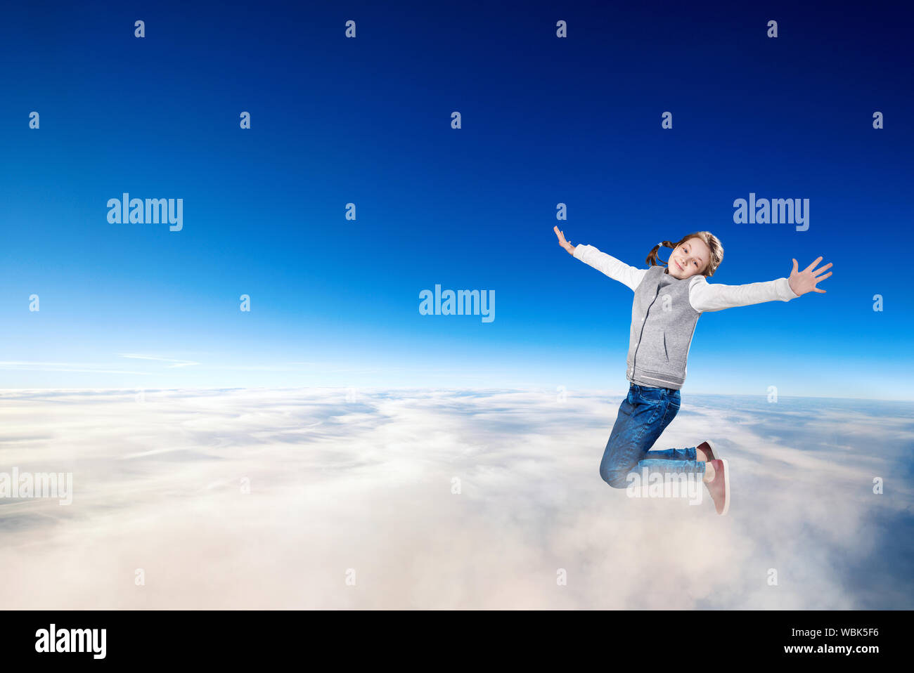 Little cute girl flying over clouds in the blue sky Stock Photo - Alamy
