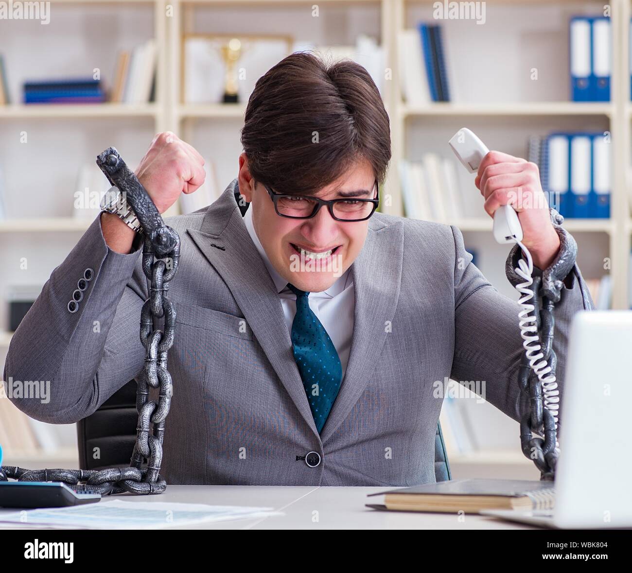 The businessman tied with chains to his work Stock Photo - Alamy