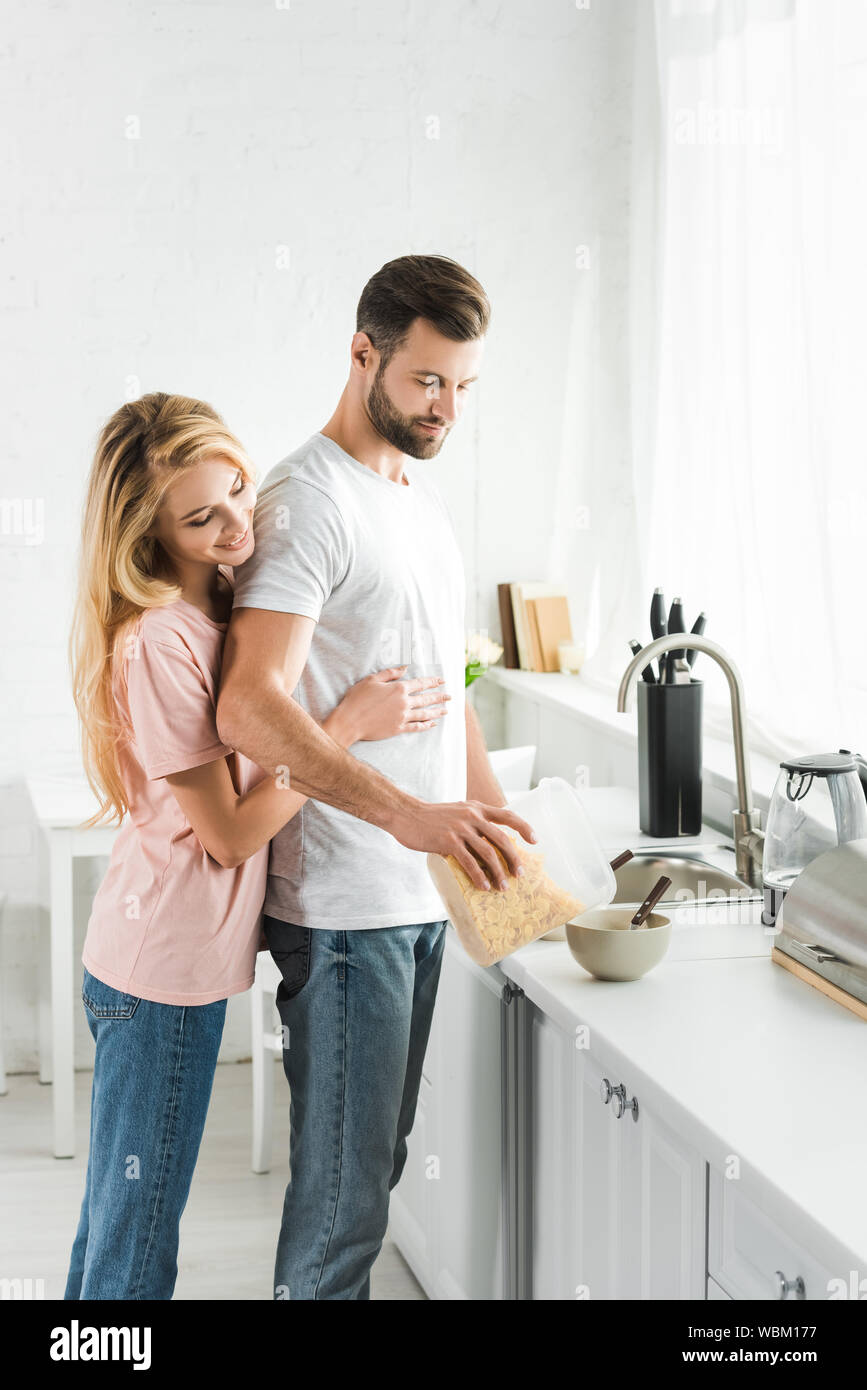woman hugging man pouring cereal during breakfast at kitchen Stock ...