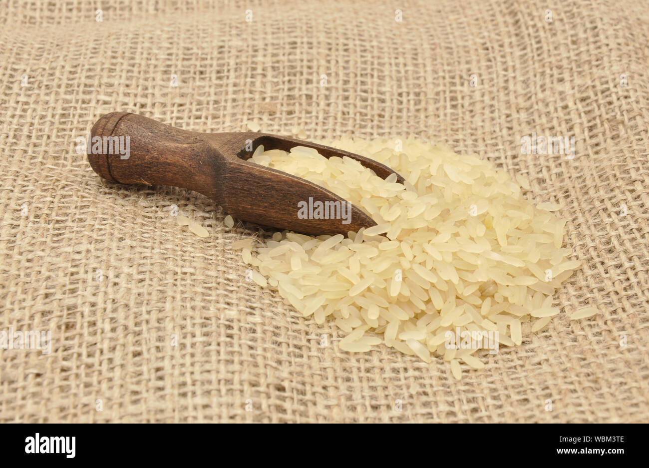 Rice in wooden scoop on rag cloth. Food background Stock Photo - Alamy