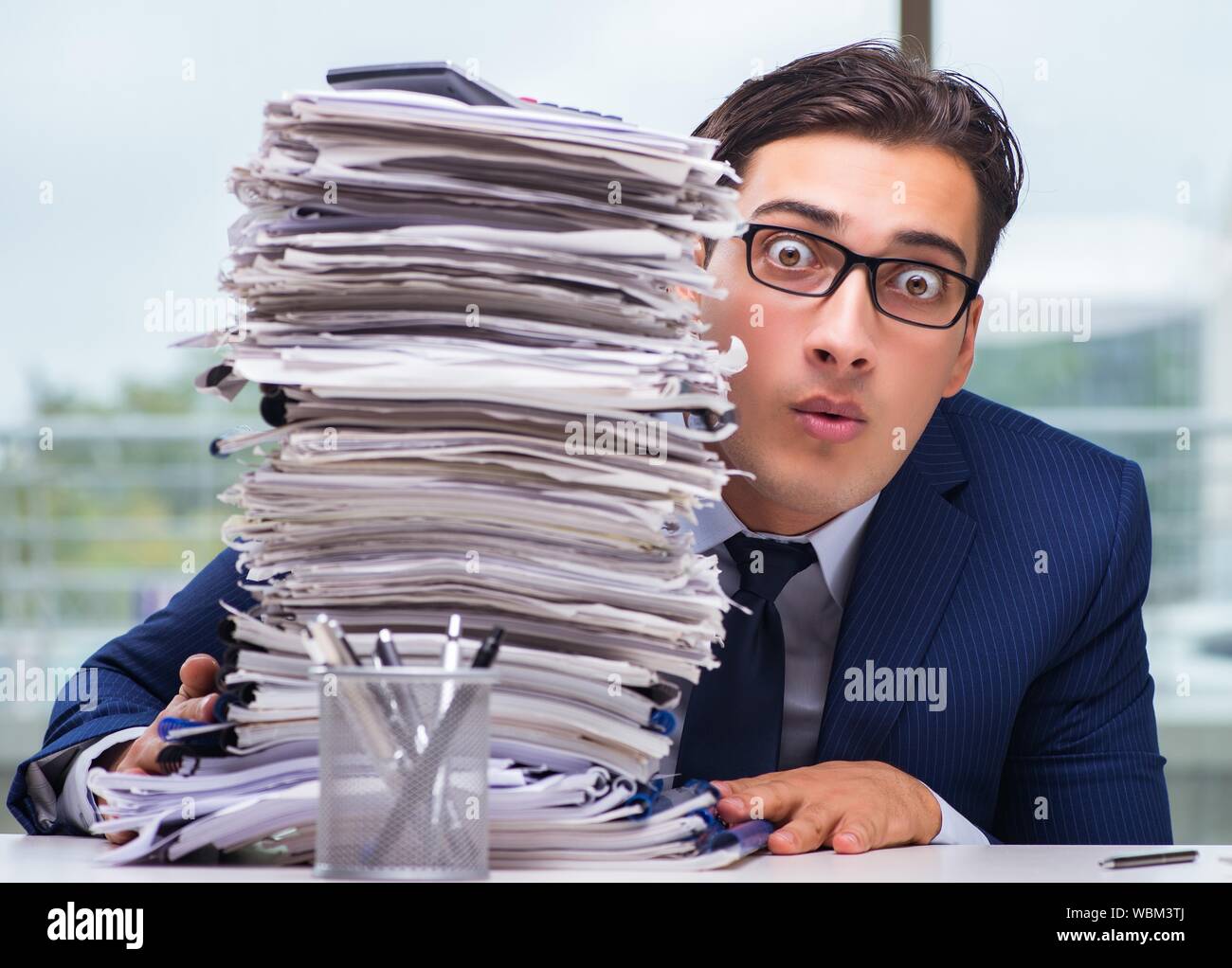 The businessman with pile stack of paper paperwork in the office Stock ...