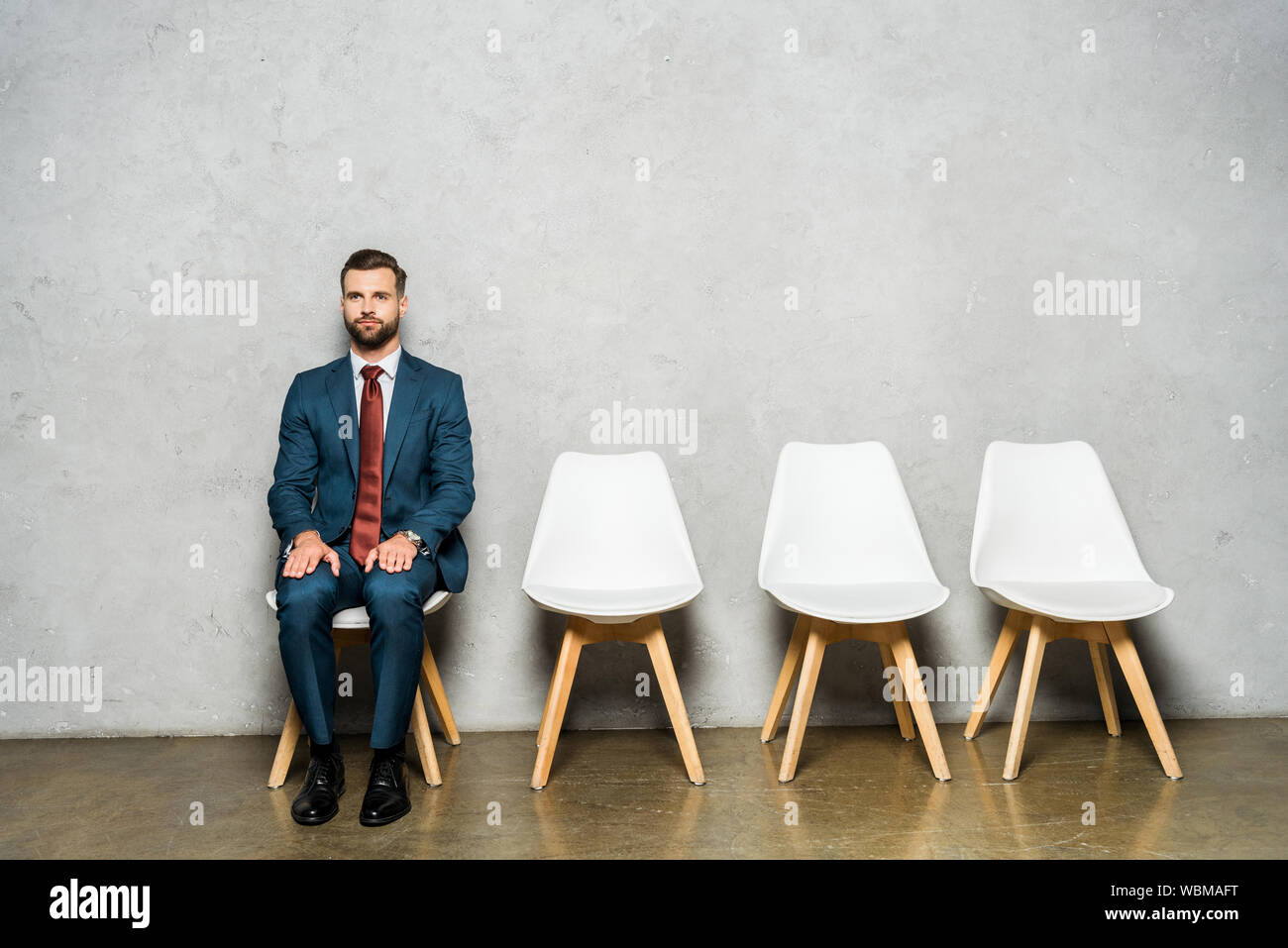 handsome bearded man sitting on chair near concrete wall Stock Photo ...