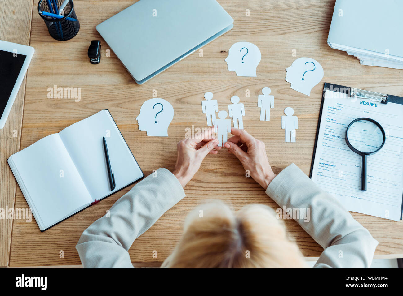 cropped view of woman holding paper human shapes near table Stock Photo ...
