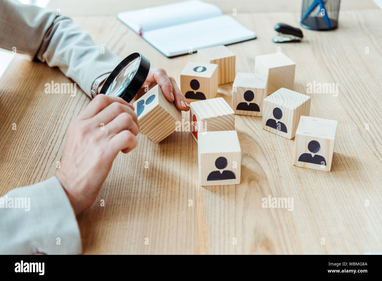 cropped view of recruiter holding magnifier near cube in office Stock ...