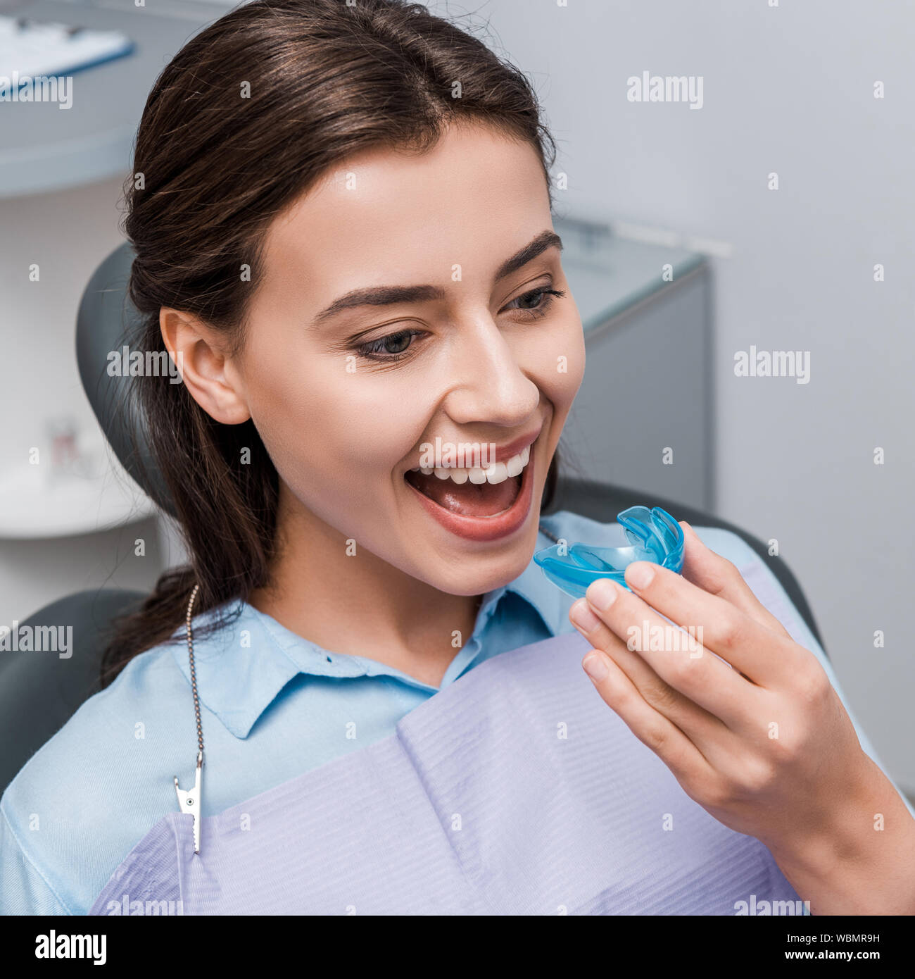 happy woman holding blue retainer in dental clinic Stock Photo - Alamy