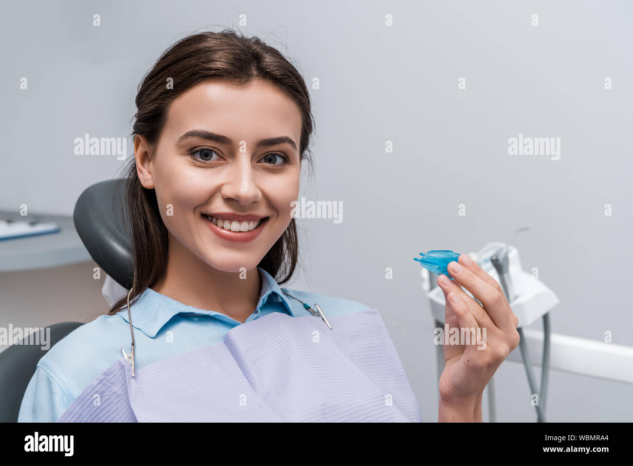 cheerful woman holding blue retainer in dental clinic Stock Photo - Alamy