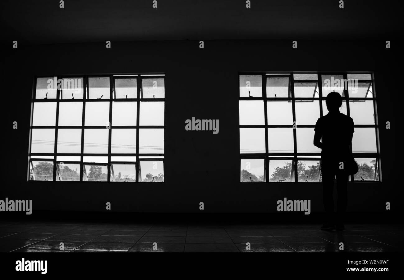 Woman standing by full length window Black and White Stock Photos ...