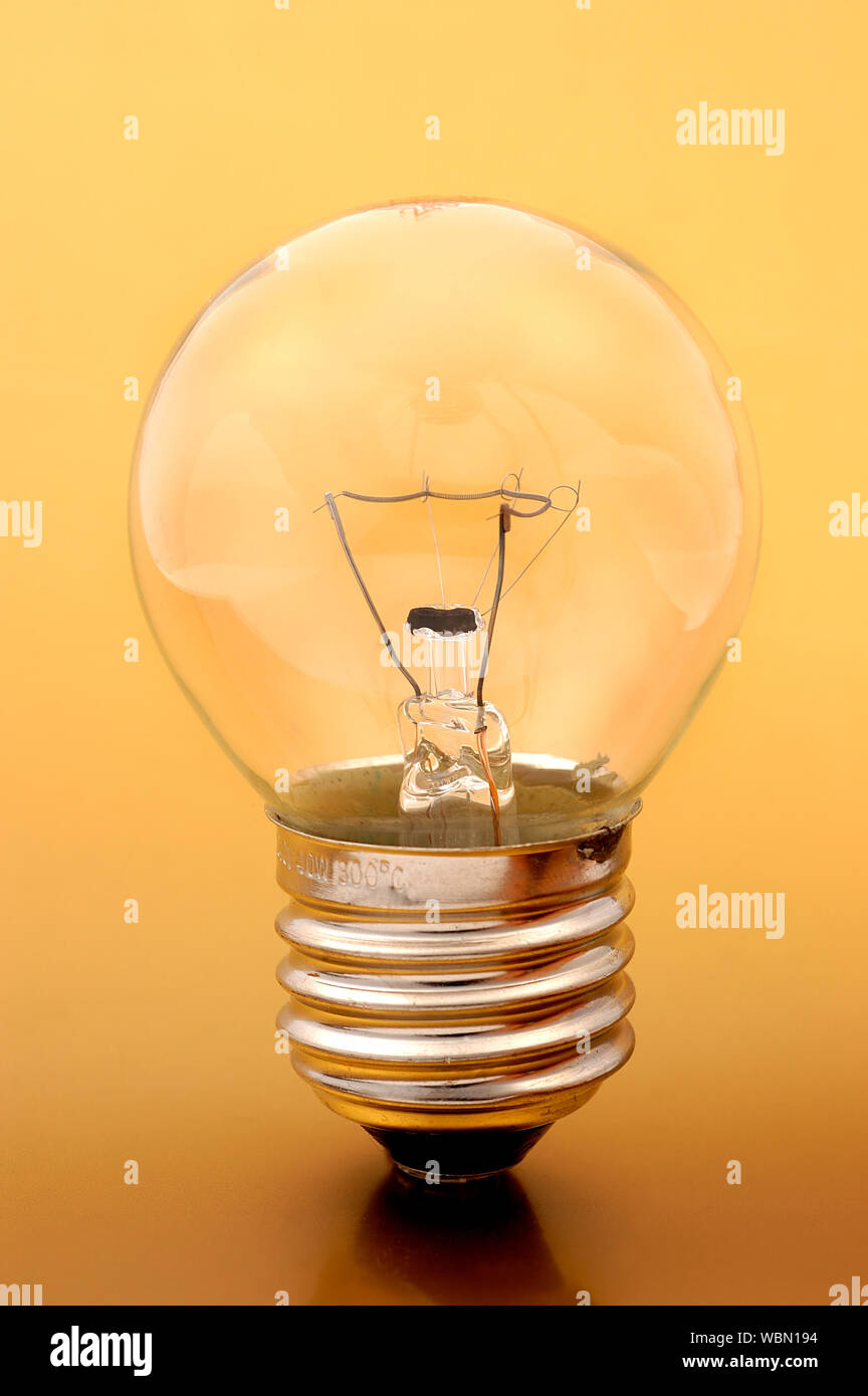 A single light bulb isolated on a gold background Stock Photo - Alamy