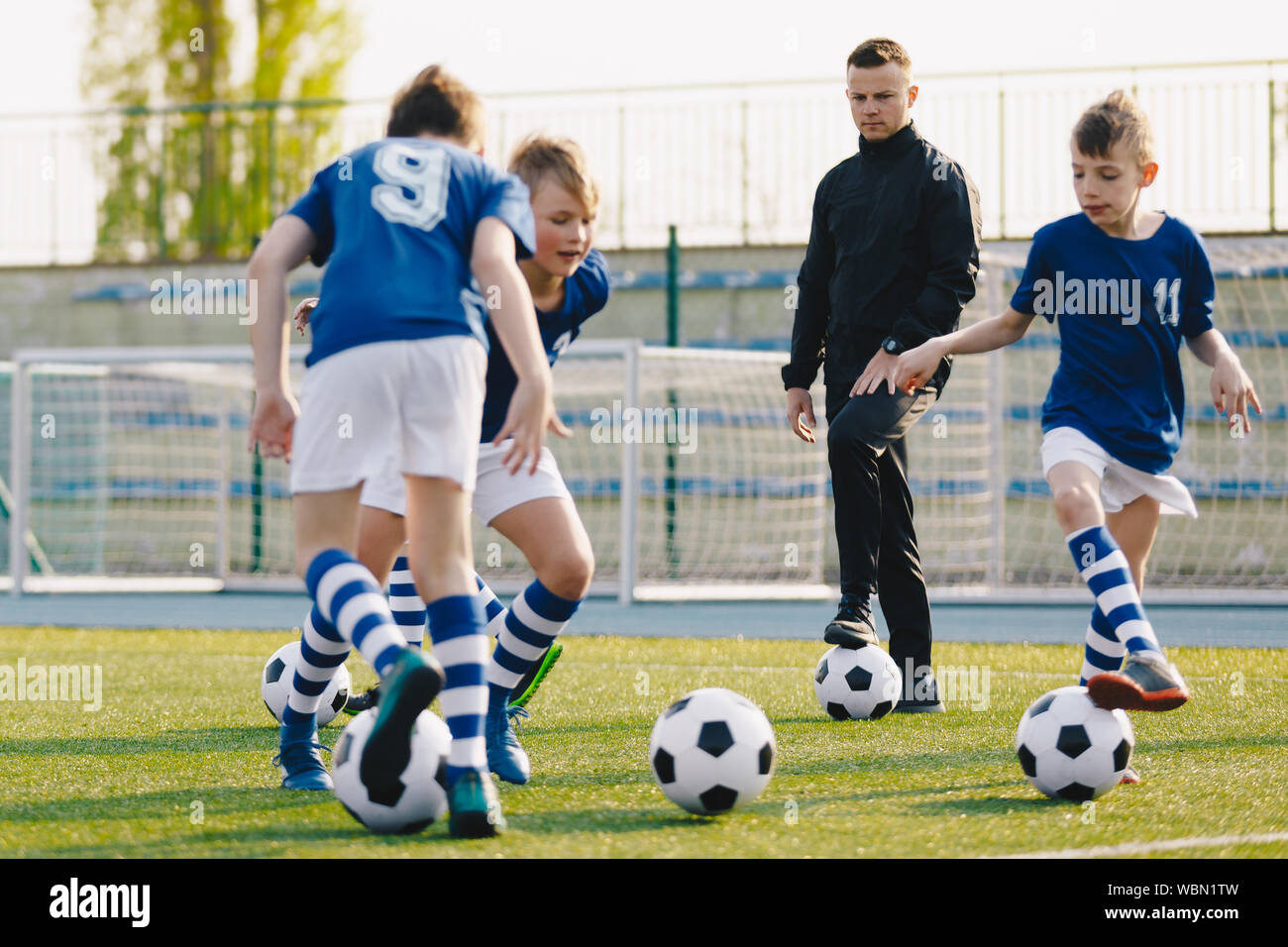 Soccer camp for kids. Boys practice football dribbling in a field ...