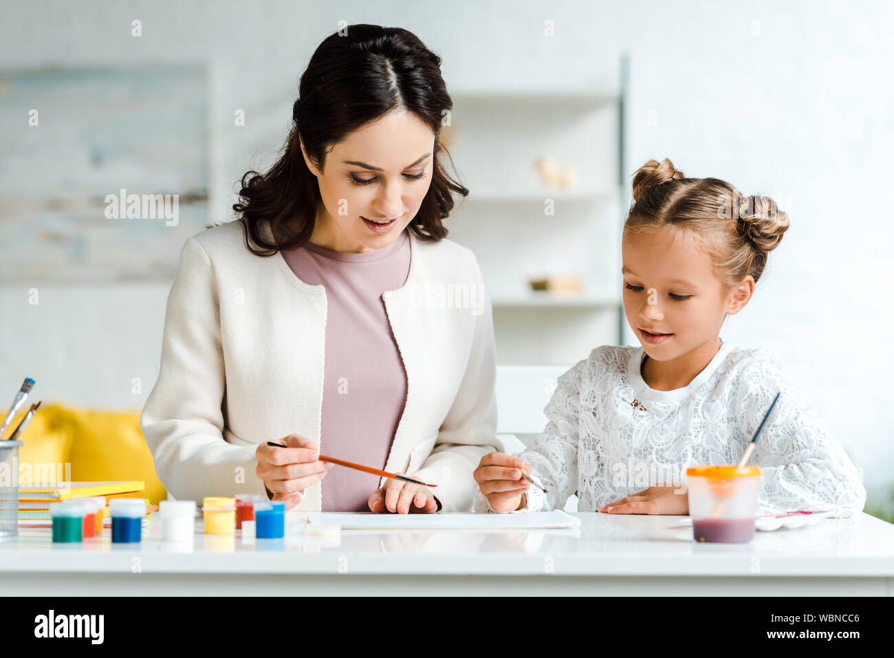 happy young woman painting with cute daughter at home Stock Photo - Alamy