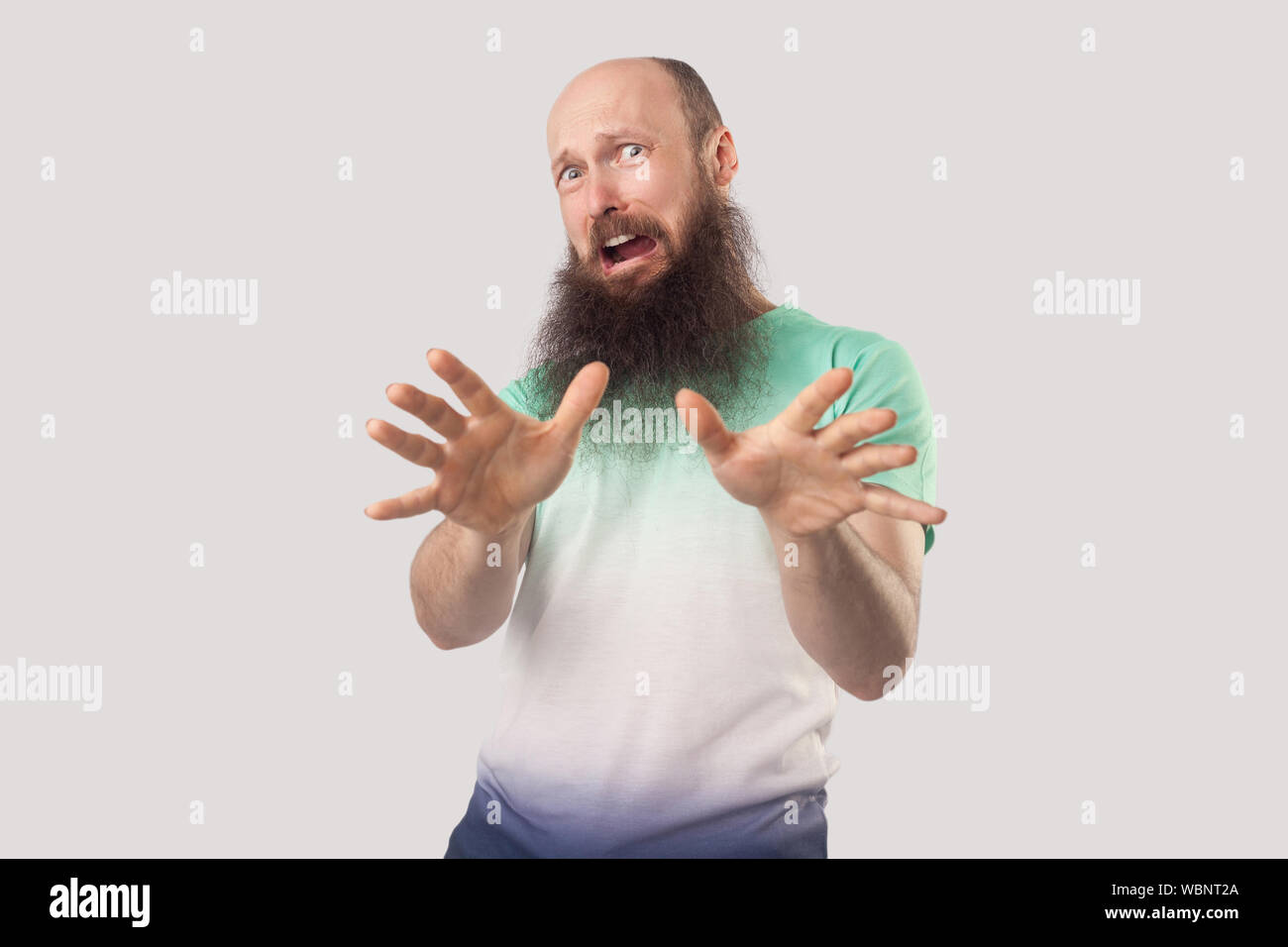 Portrait of scared middle aged bald man with long beard in light green ...