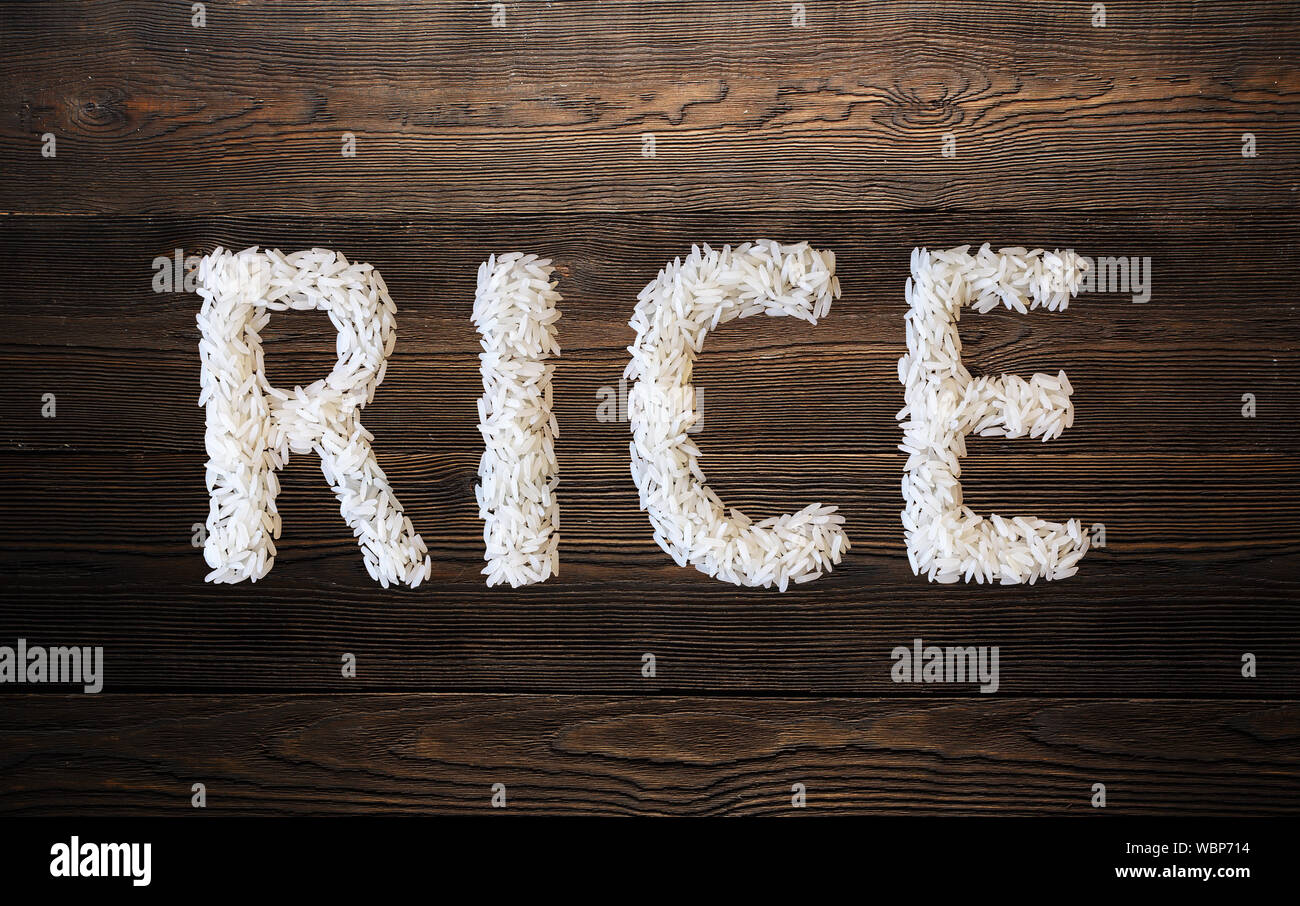 "RICE" word written with grains of rice, isolated on a wooden texture ...
