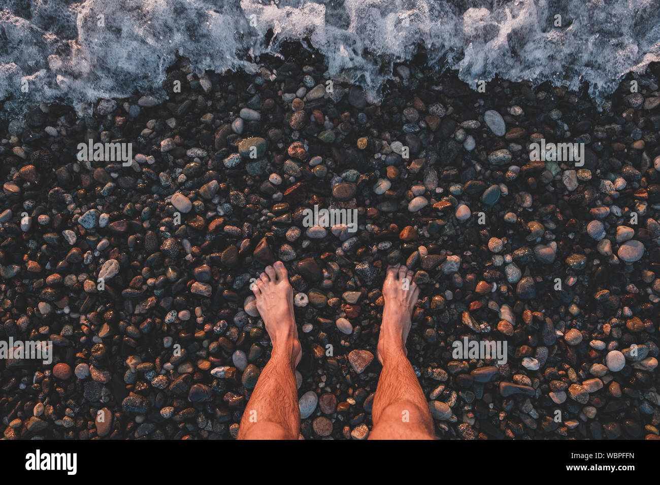 Standing on pebble by the sea, point of view. Male legs on the beach ...