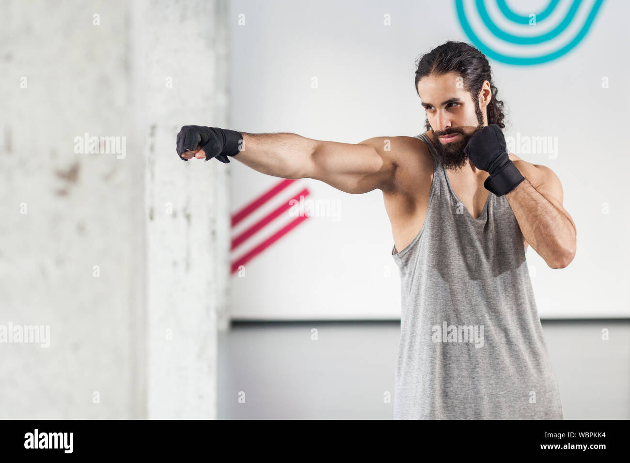 Portrait of muscular young man with curly long hair standing and ...