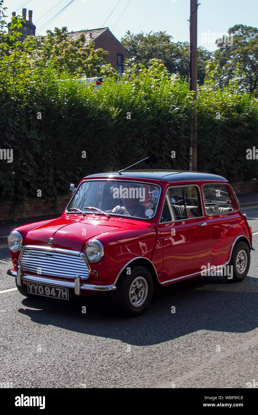 1970 70s red 998cc Morris Mini Cooper driving around the town centre ...