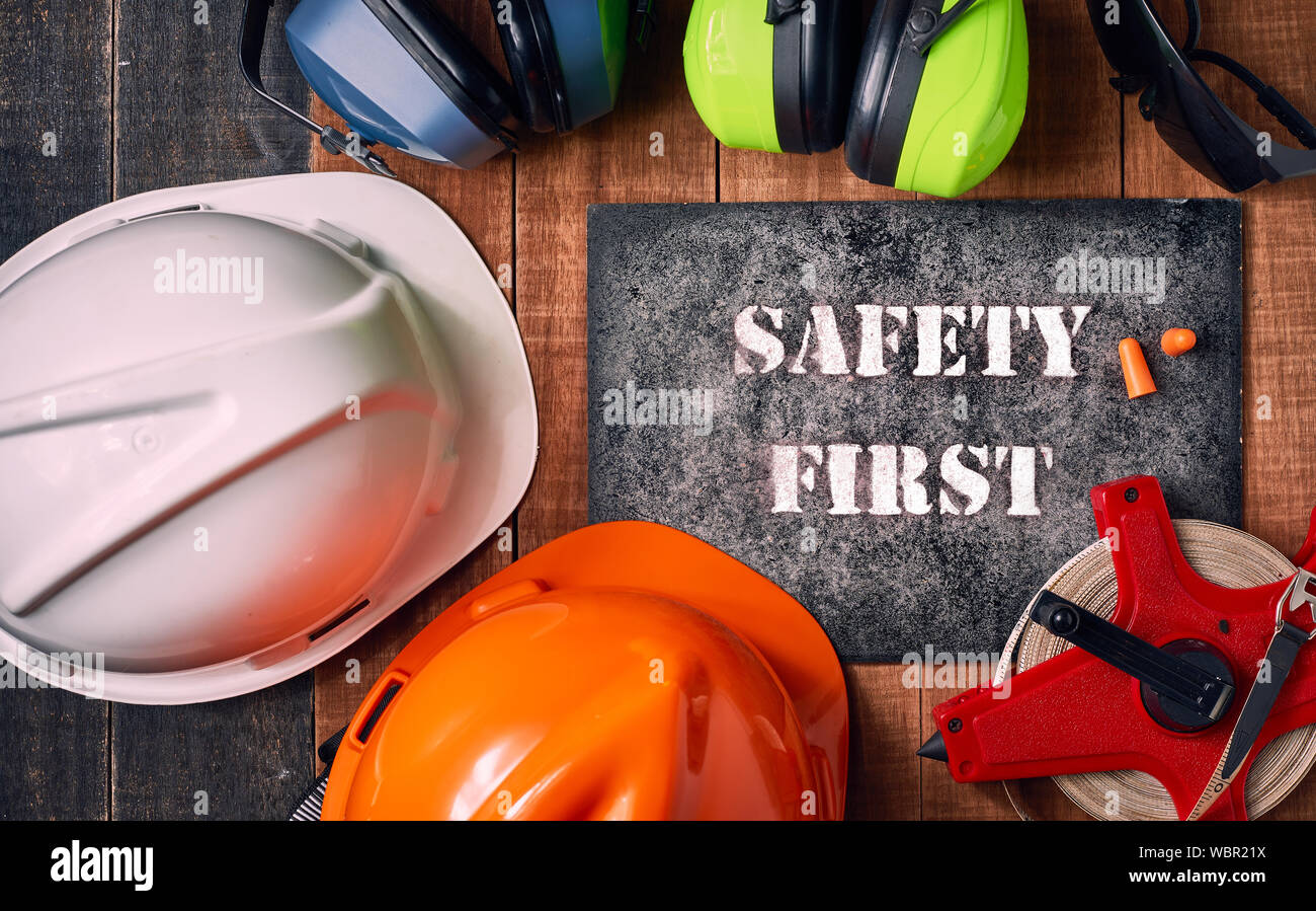 Safety first sign with personal protective equipment on wooden ...