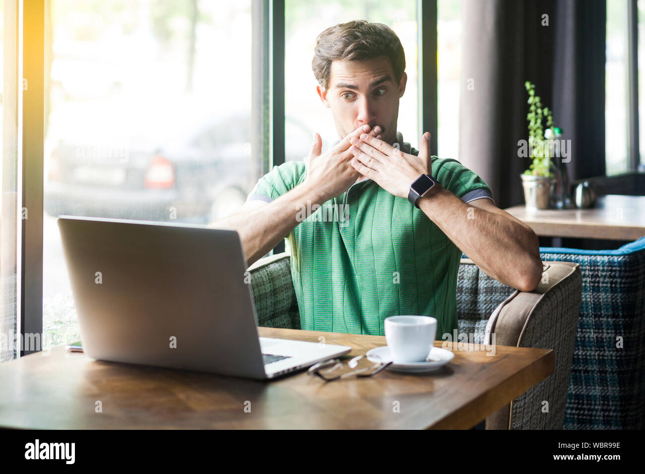 I will be quiet! Young shocked businessman in green t-shirt sitting ...