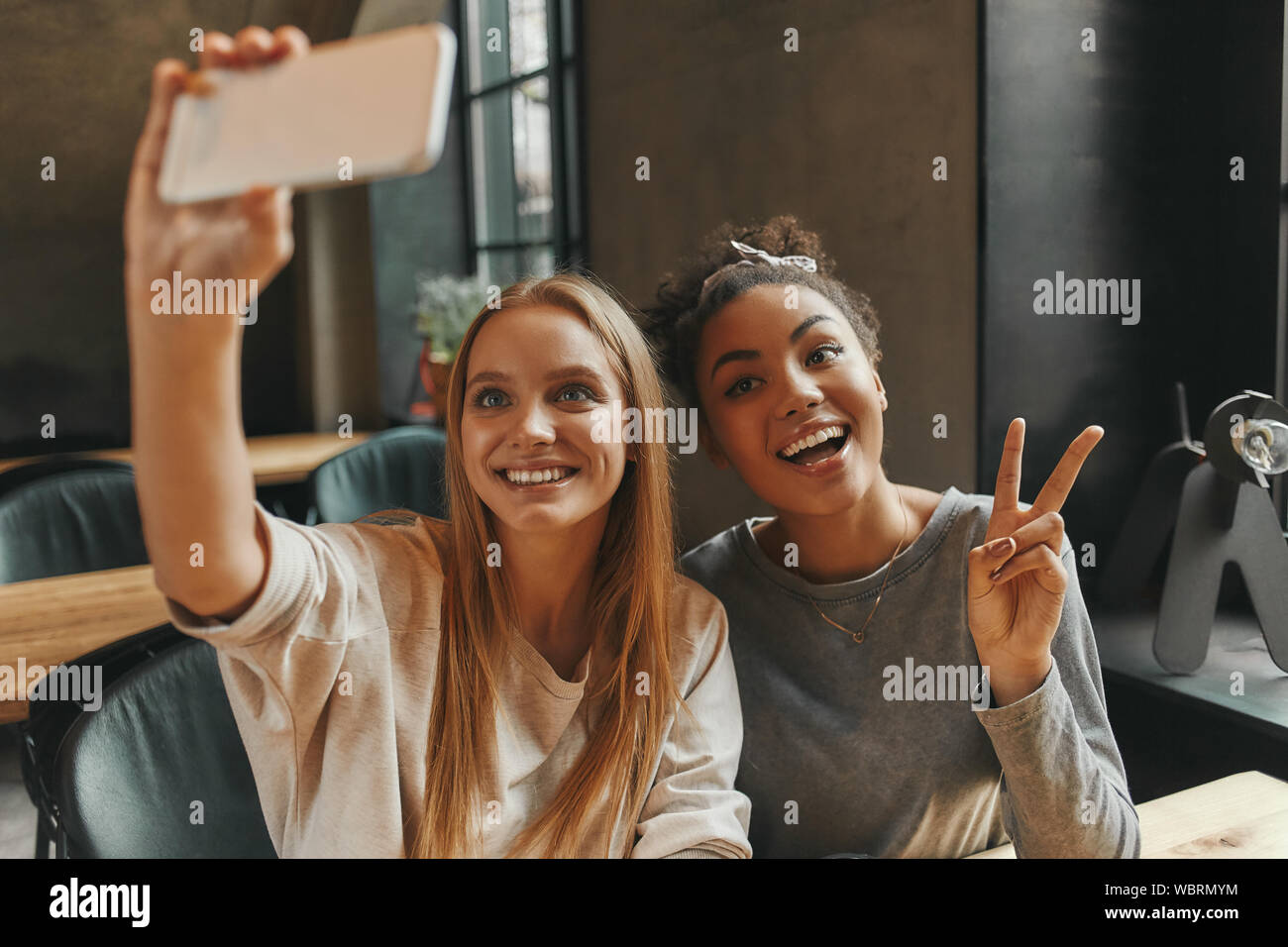 Portrait Of Two Multiracial Young Women Taking Selfies Using Smartphone