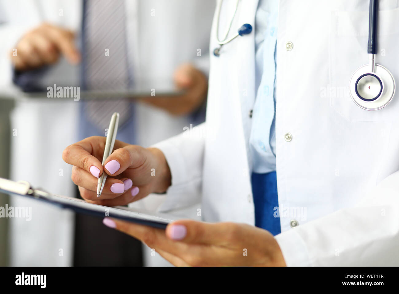 Arms of GP signing with silver pen important document Stock Photo - Alamy