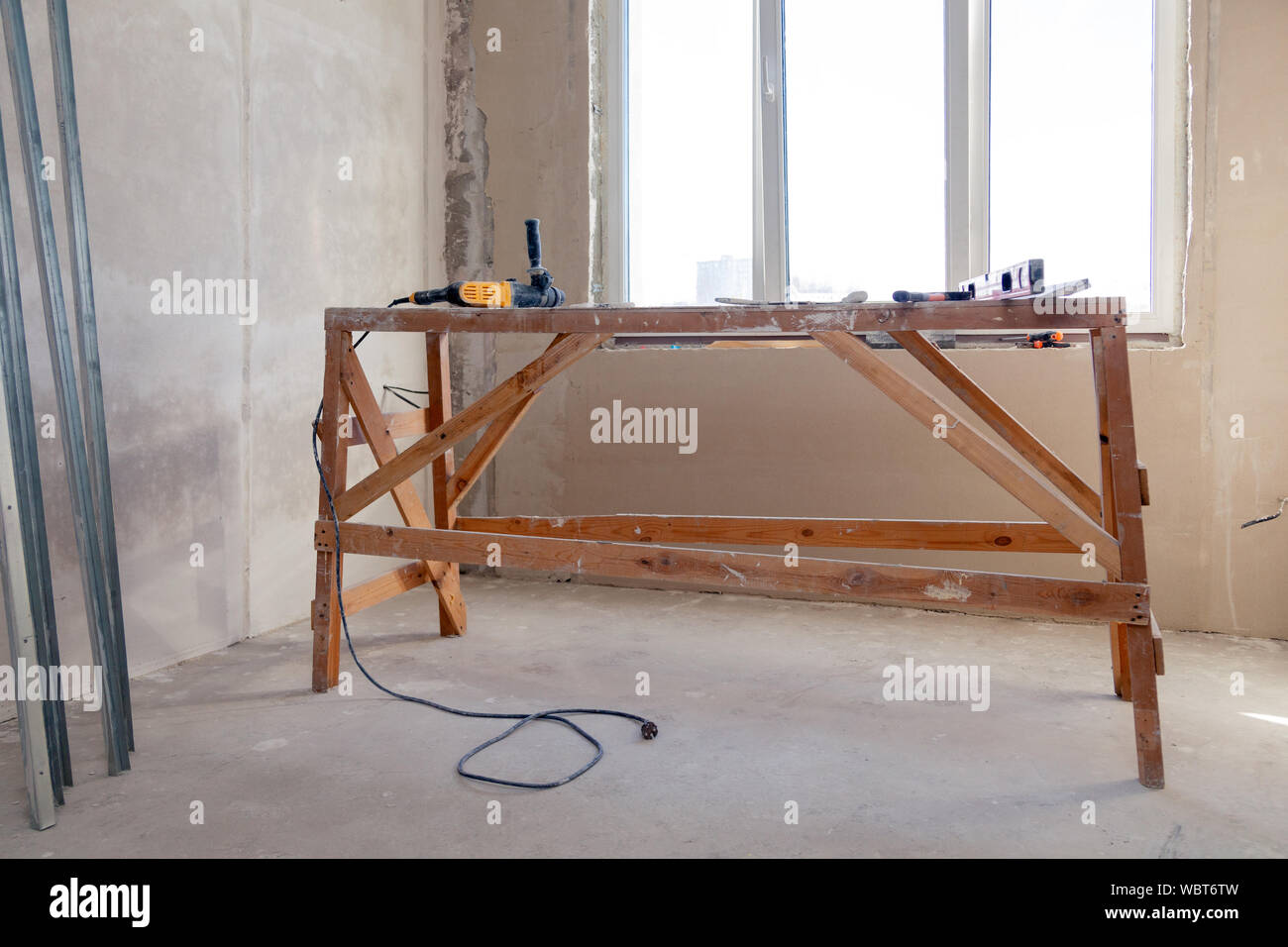 Wooden scaffolding stand at the window in a large empty room, repair ...