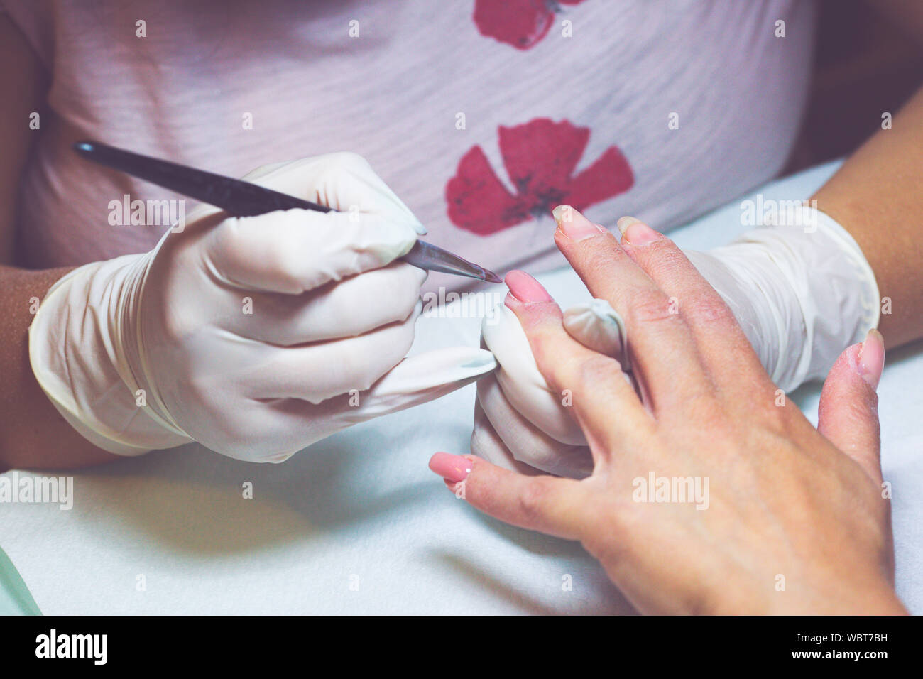 Nail beautician at work while performing the decoration and maintenance ...