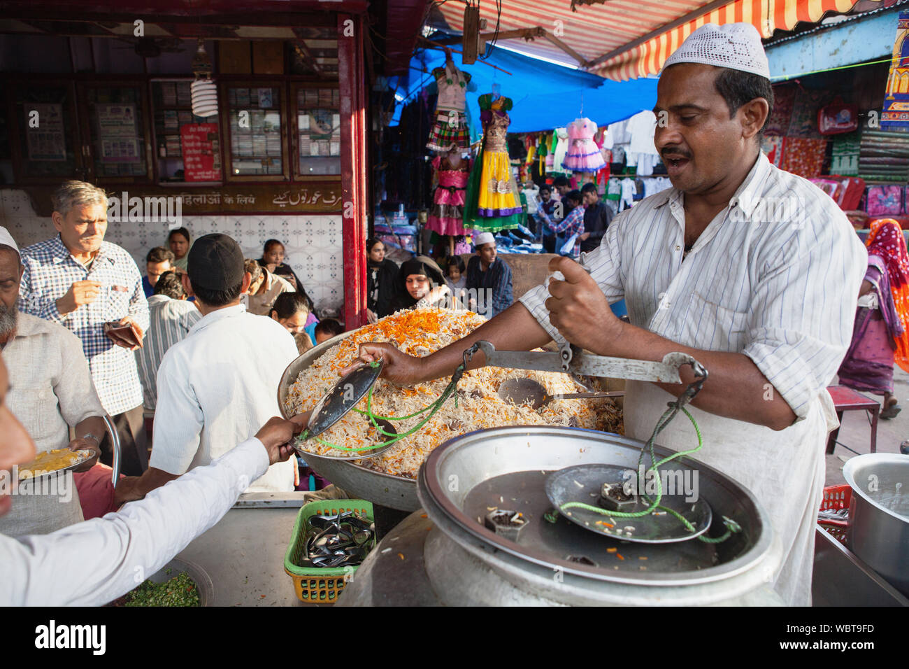 India, Delhi, A muslim cook prepares to weigh a serving of rice biryani ...