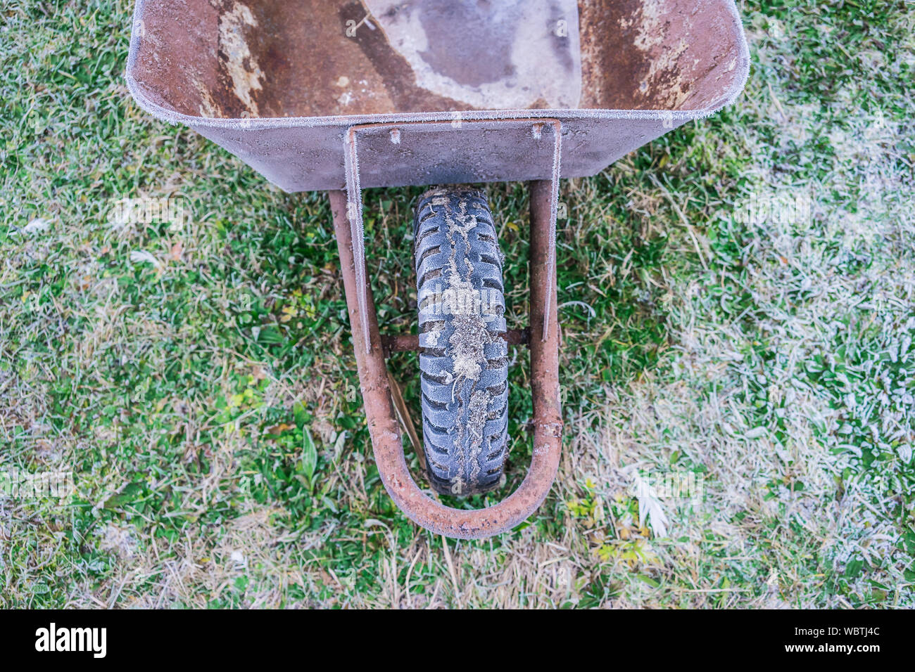Forgotten old rusty damaged freezed wheelbarrow at winter, close up to ...