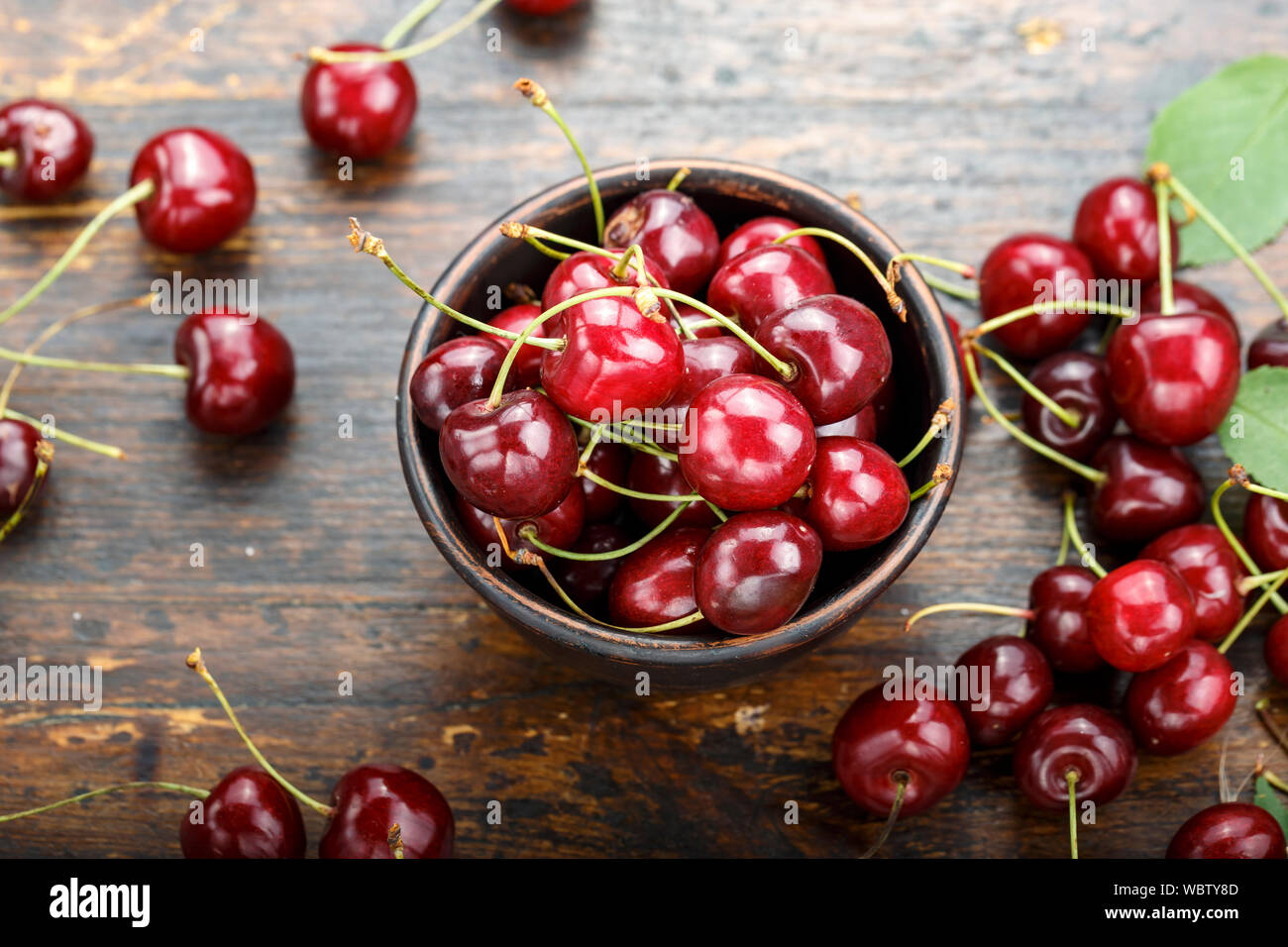 sweet cherries in a plate on a shabby brown wooden background. place ...