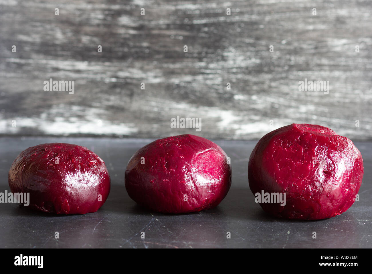 three roots of cooked peeled beet in a row on black background Stock ...