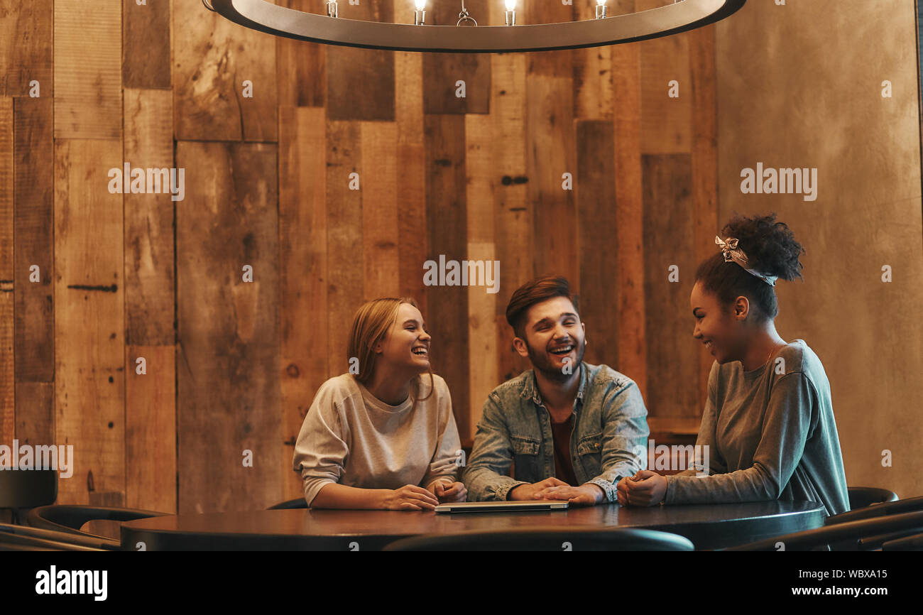 Portrait of three colleagues laughing and talking to each other as they ...