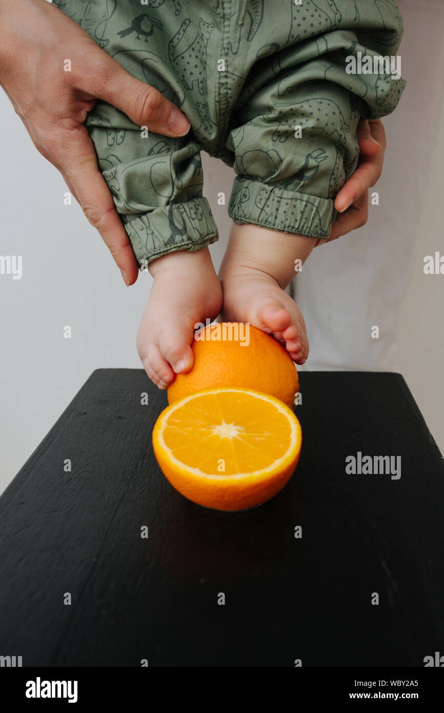 Baby's feet with orange close up photo Stock Photo - Alamy