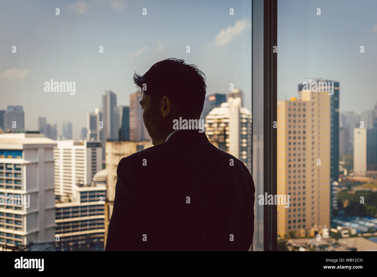 Businessman looking through window Stock Photo - Alamy